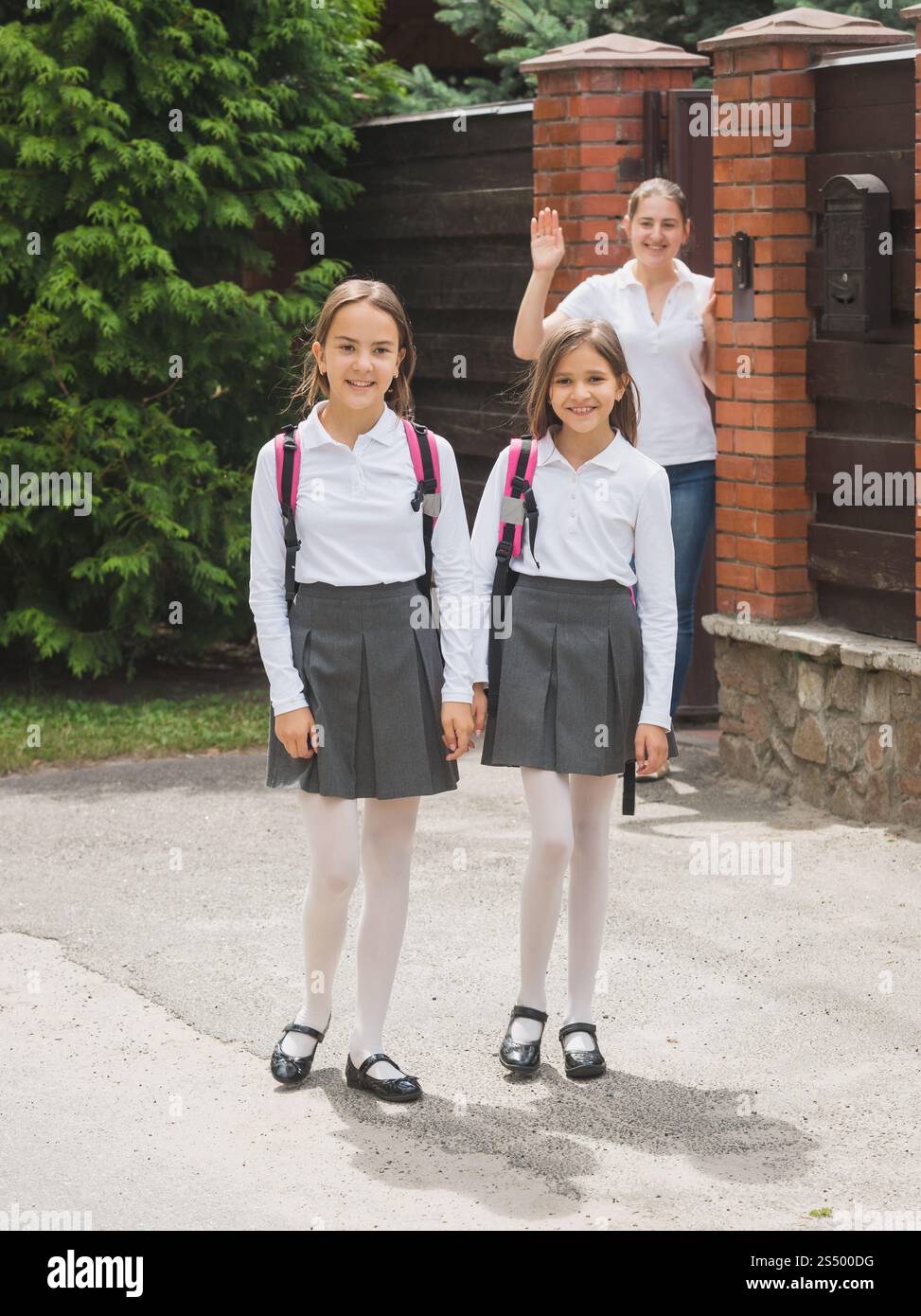Mother waving with hand to her daughters walking to school Stock Photo - Alamy