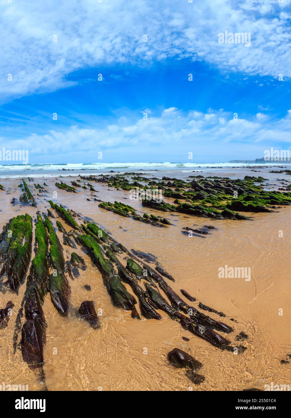 Rock formations on sandy beach and blue sky with cumulus clouds ...
