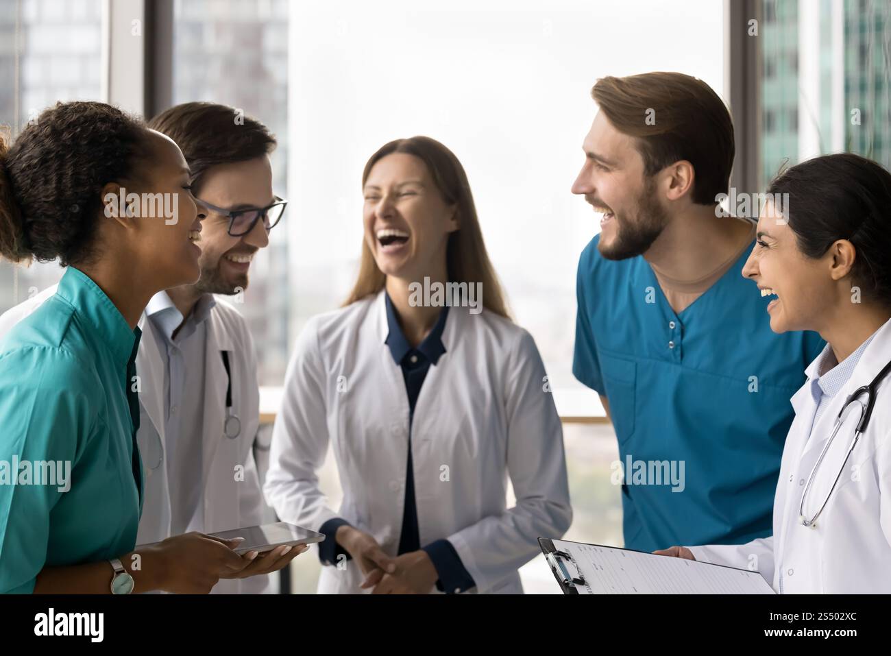 Happy clinic staff members laughing gathered together in clinic office ...