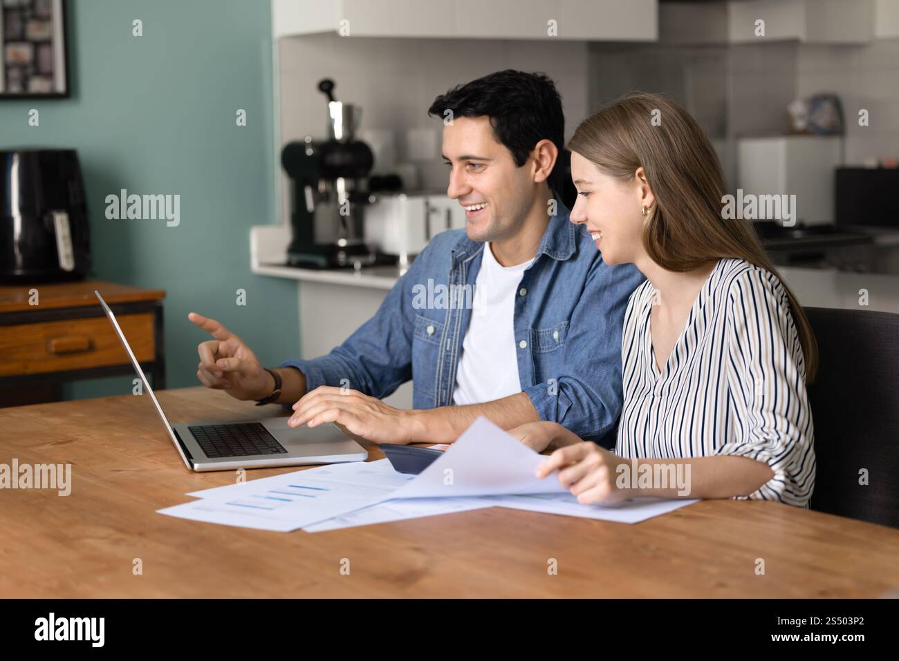 Cheerful young couple of new home owners paying paper bill Stock Photo ...
