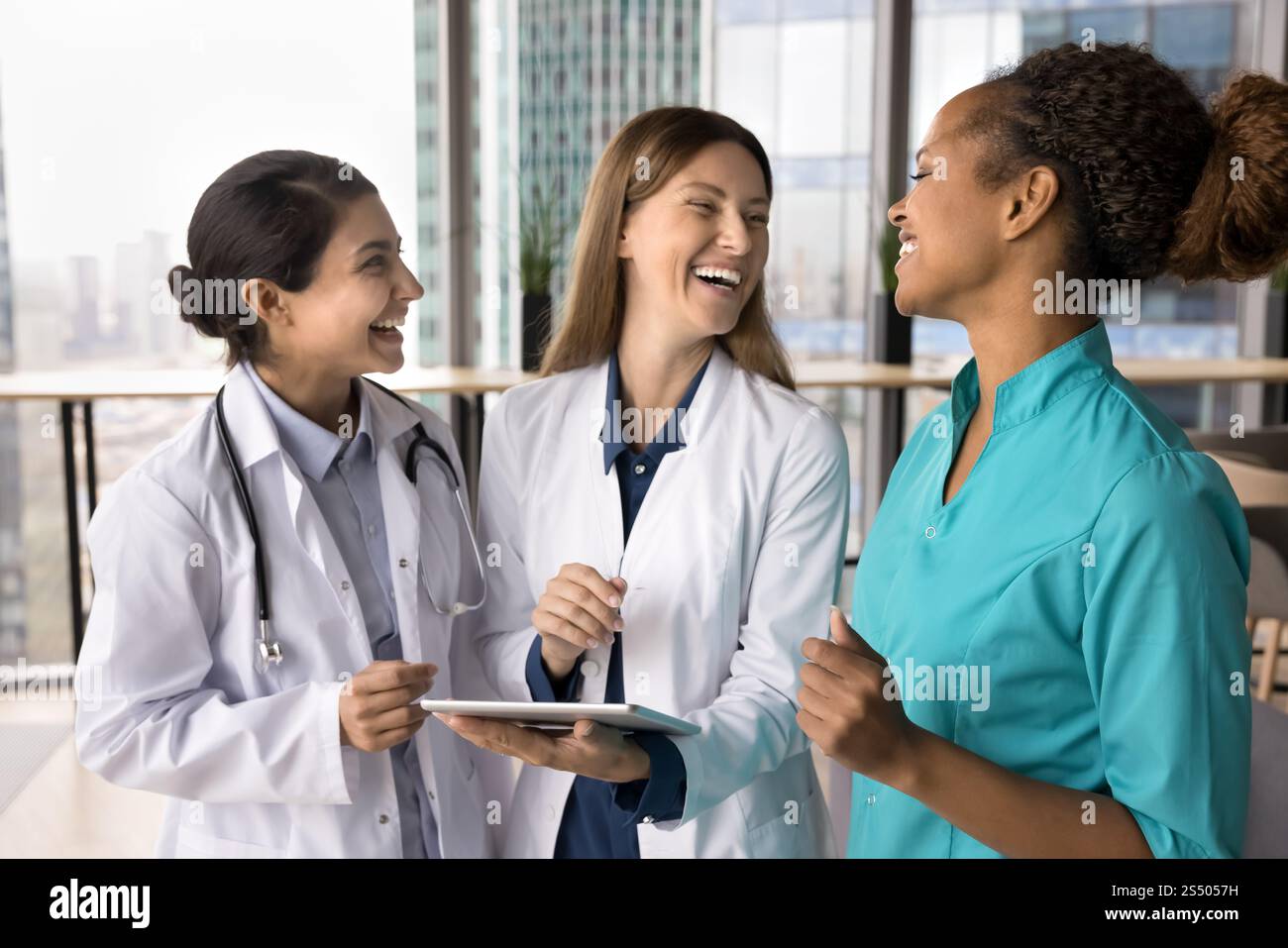 Three general practitioners colleagues laughing, lead conversation ...