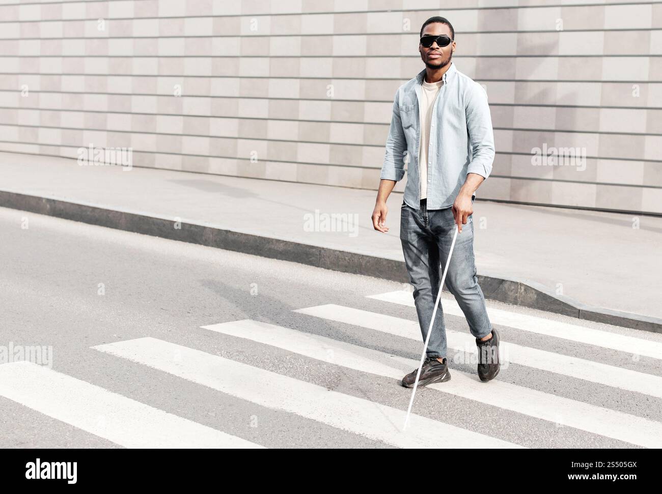 Young black man with visual disability wearing dark glasses, using ...