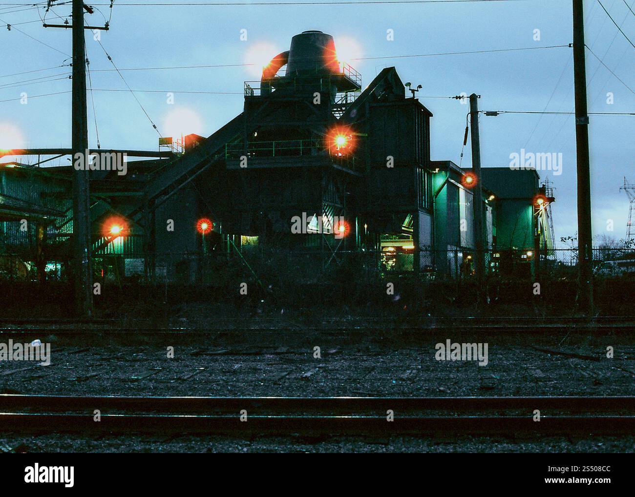 Moody industrial refinery by train tracks Stock Photo - Alamy