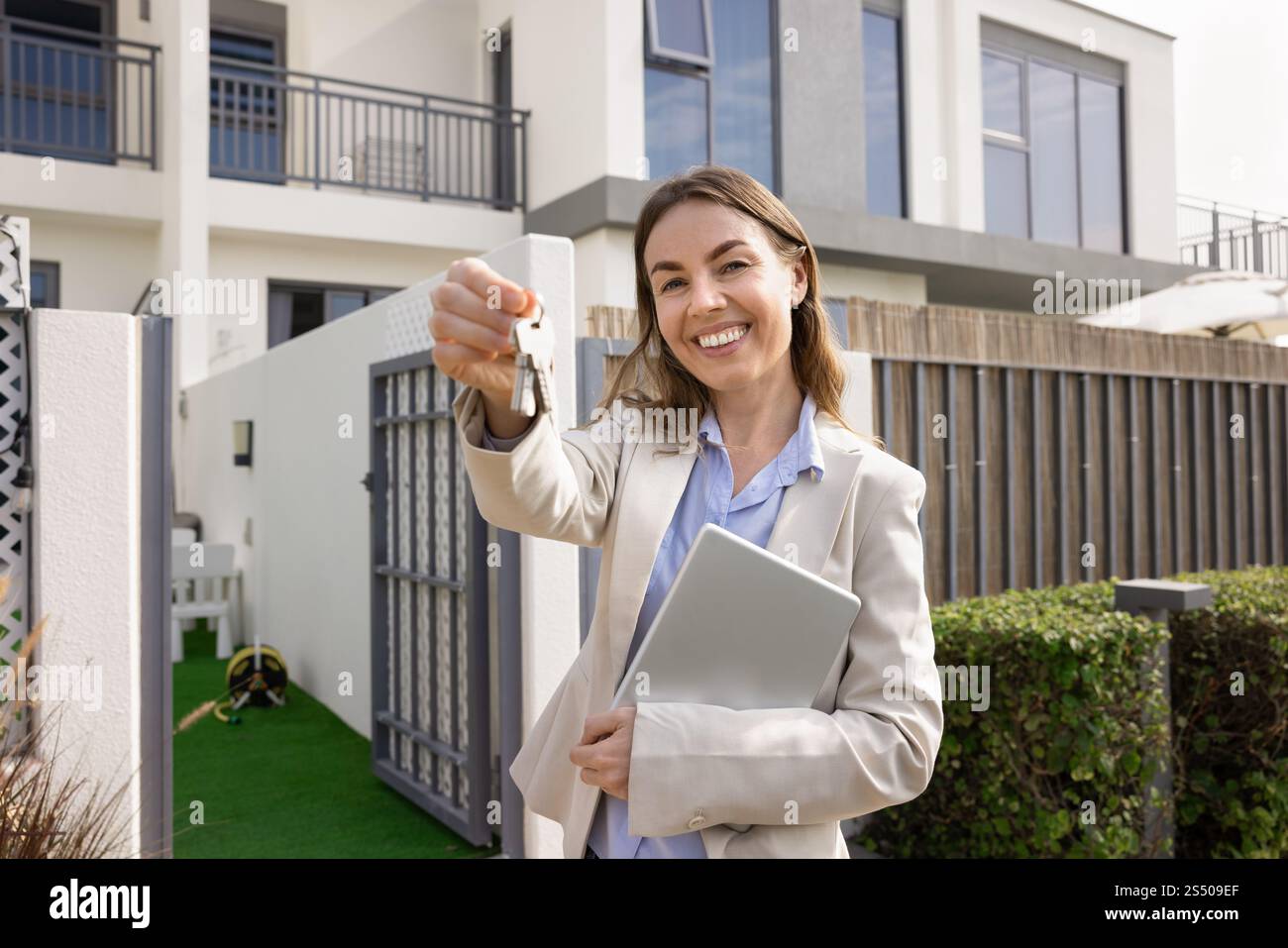 Happy real estate agent woman offering key from new home Stock Photo ...