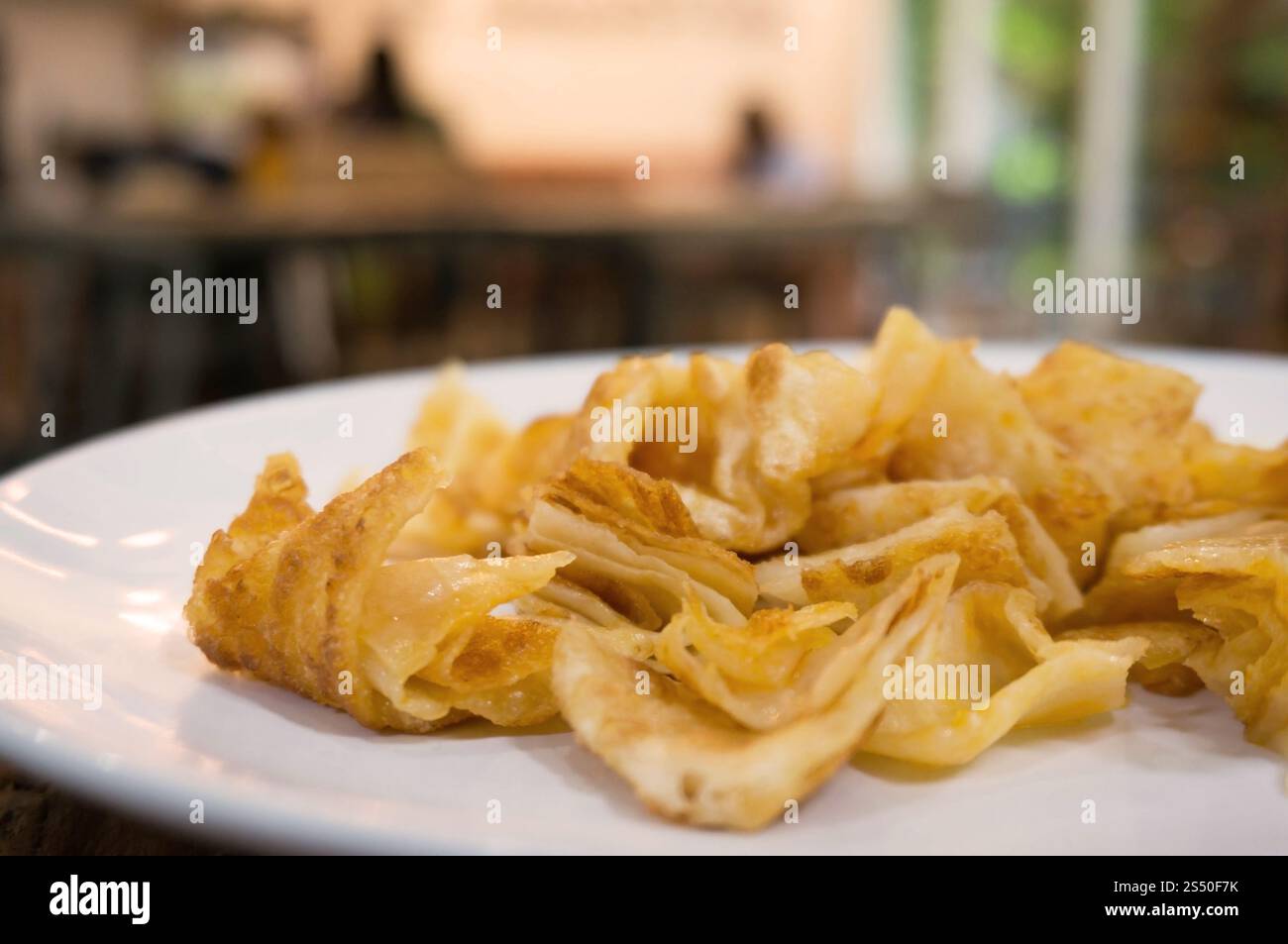 Stack of fried crispy roti indian bread on white plate with sweet milk ...