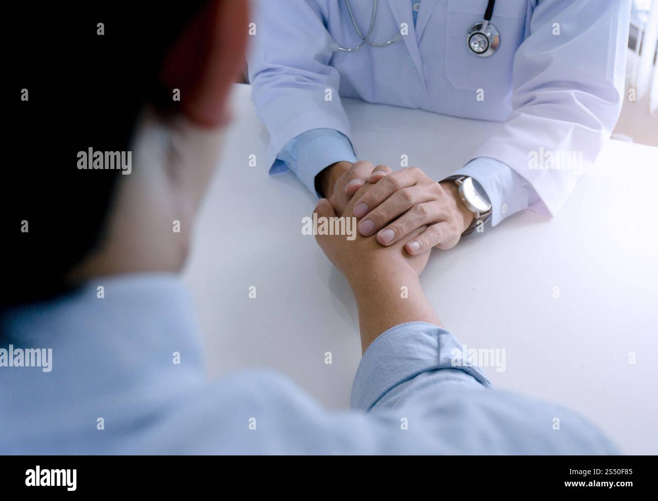 Doctor holding patients hand, and reassuring his male patient helping ...