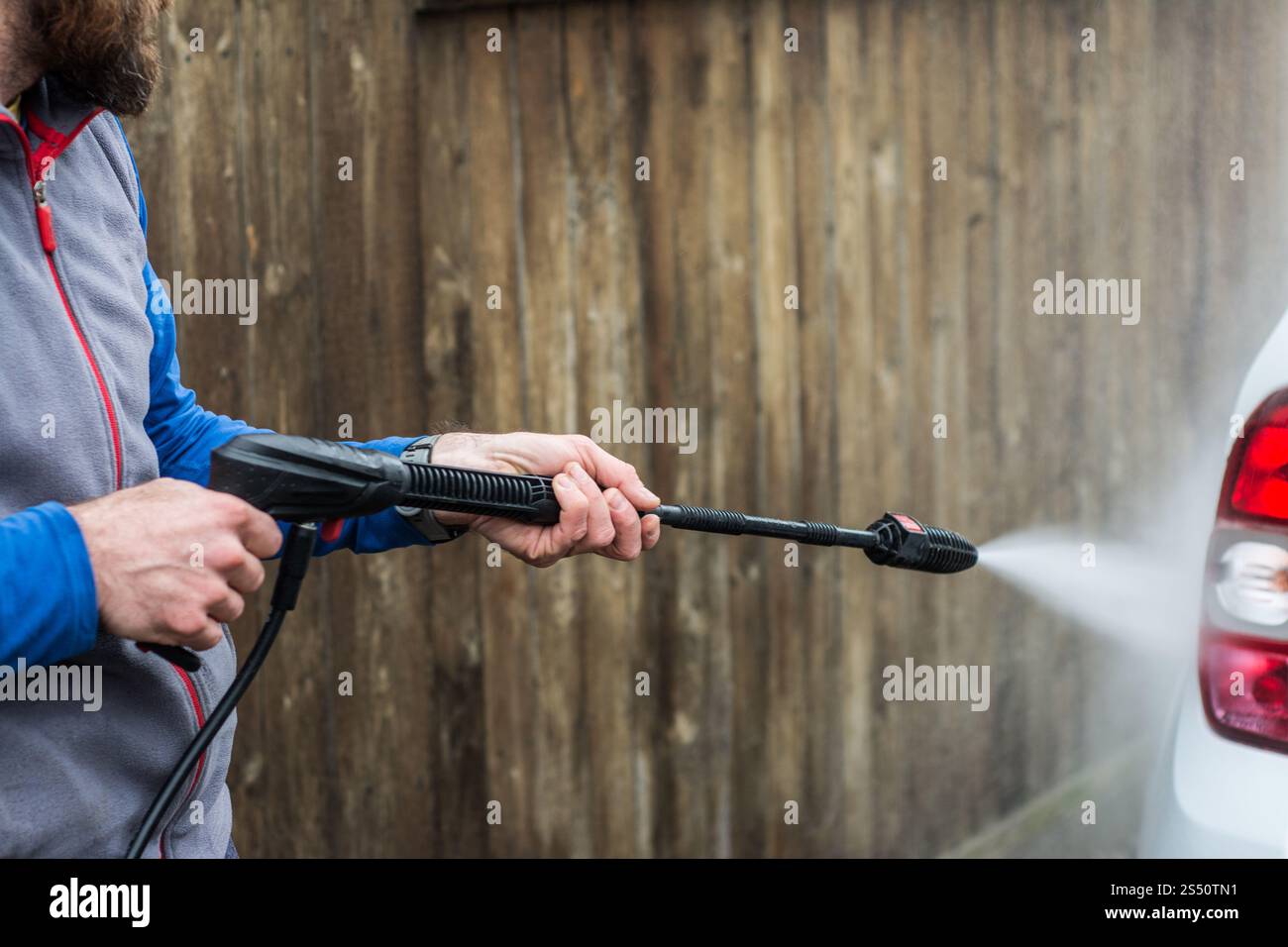 Close up photo of a man hands washes his car with a large head of water ...