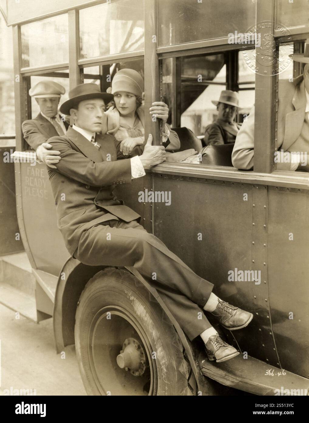Movie comedian Buster Keaton sits stoically on the fender of a bus. A ...