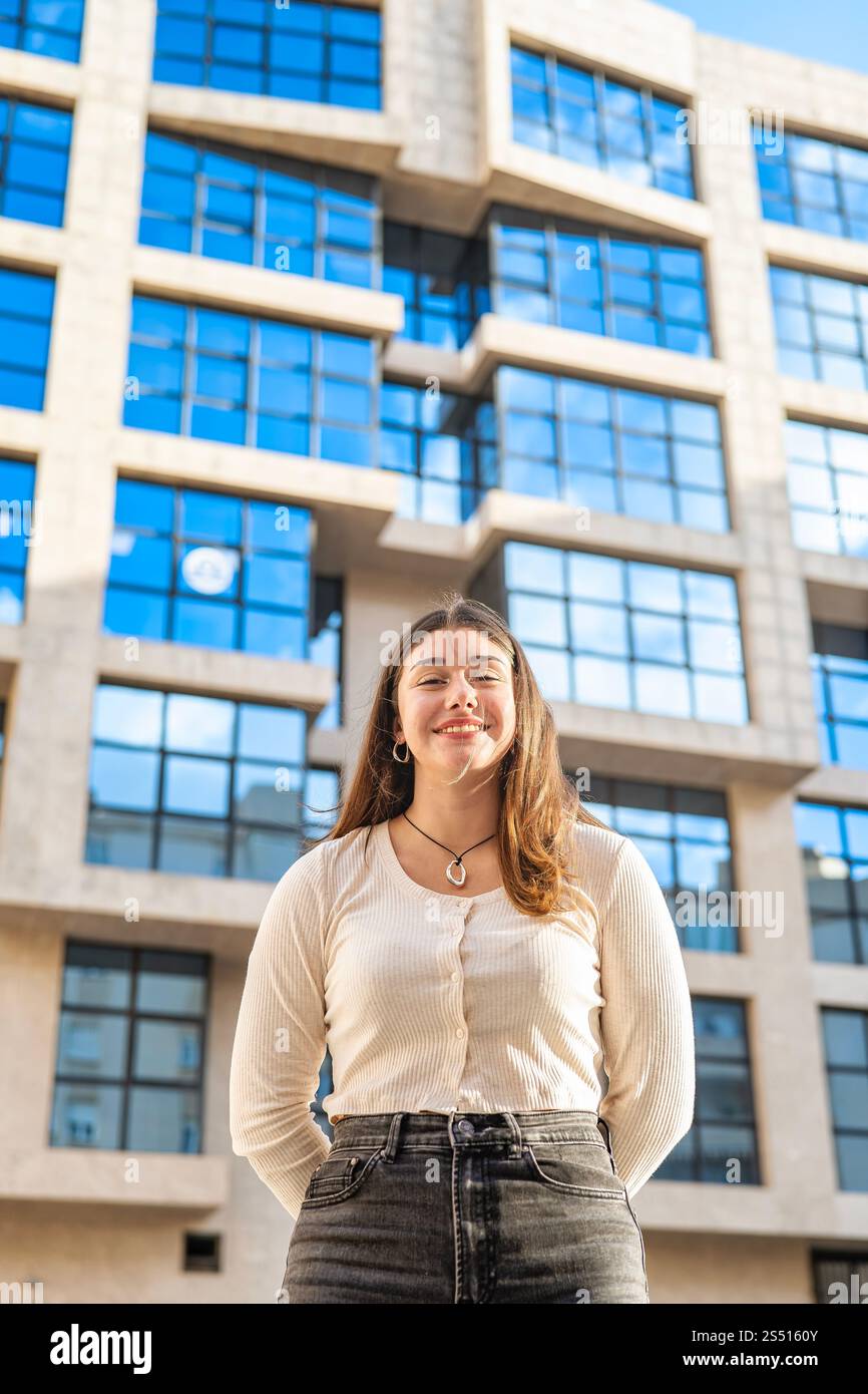 Smiling Caucasian girl in front of an office building, standing facing ...