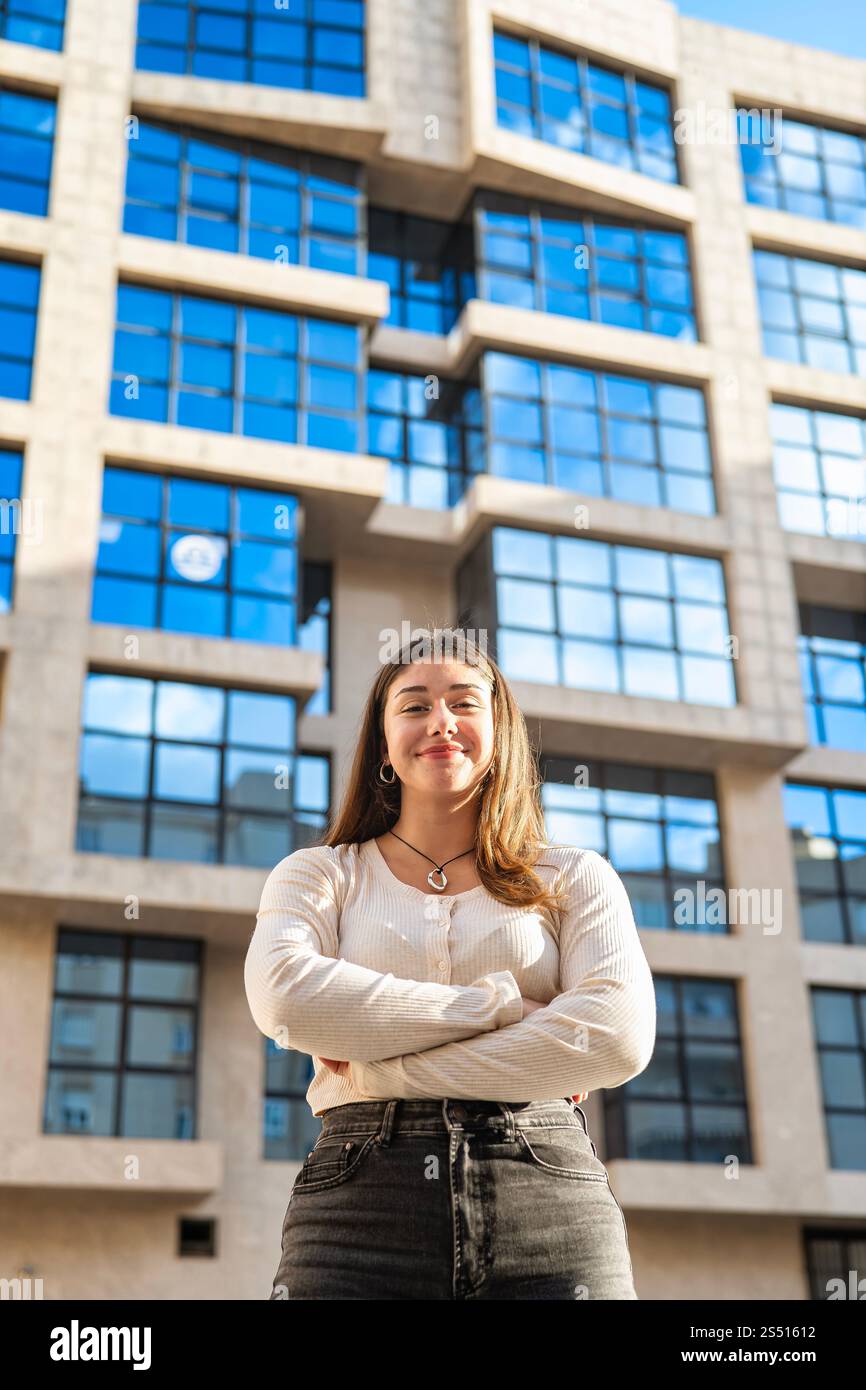 A Caucasian girl is standing in front of a glass building, long hair ...