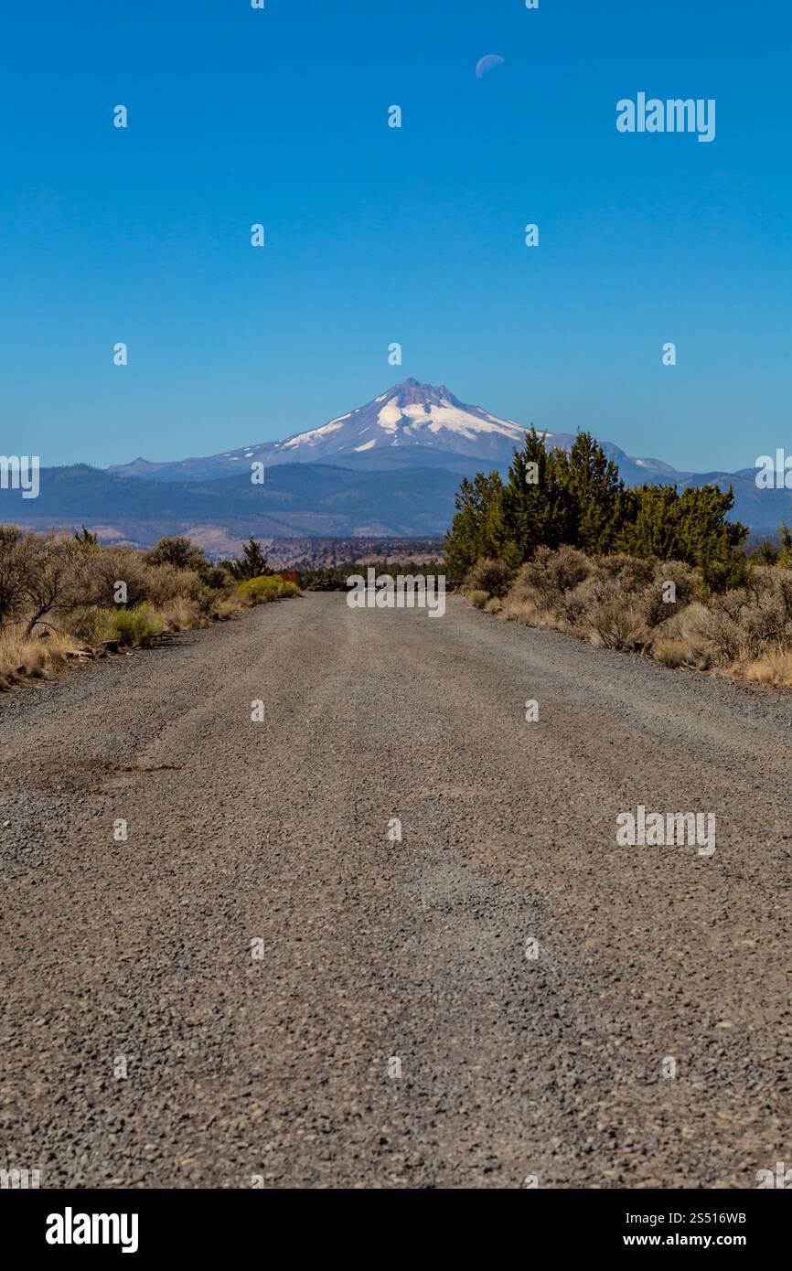 Remote Gravel Road Leading to Snow-Capped Mountain Under Clear Blue Sky ...