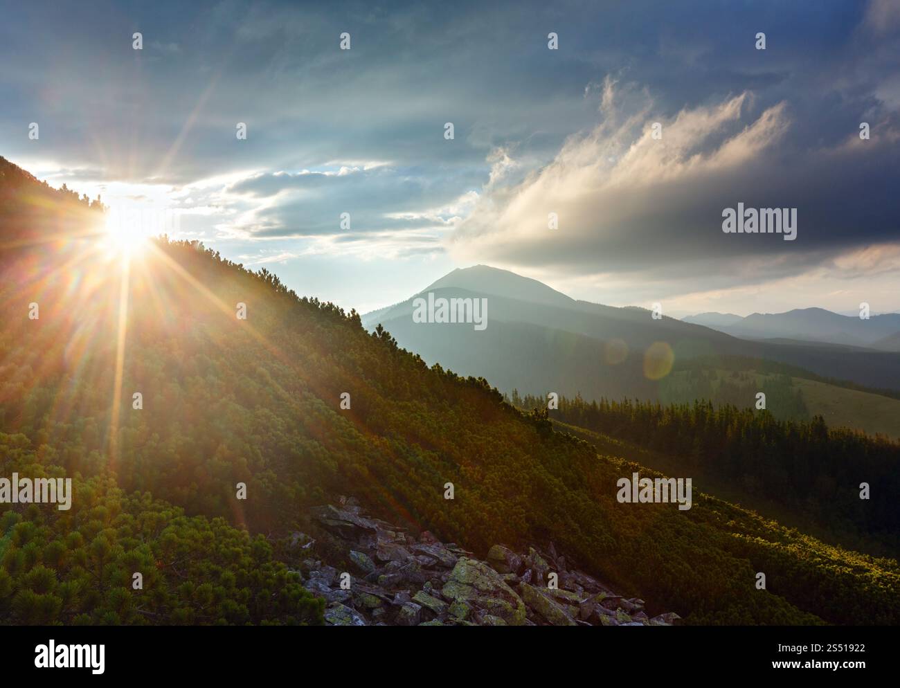 Last sun rays in evening sky with clouds above Syniak mountain. Summer sunset view from Homiak ...