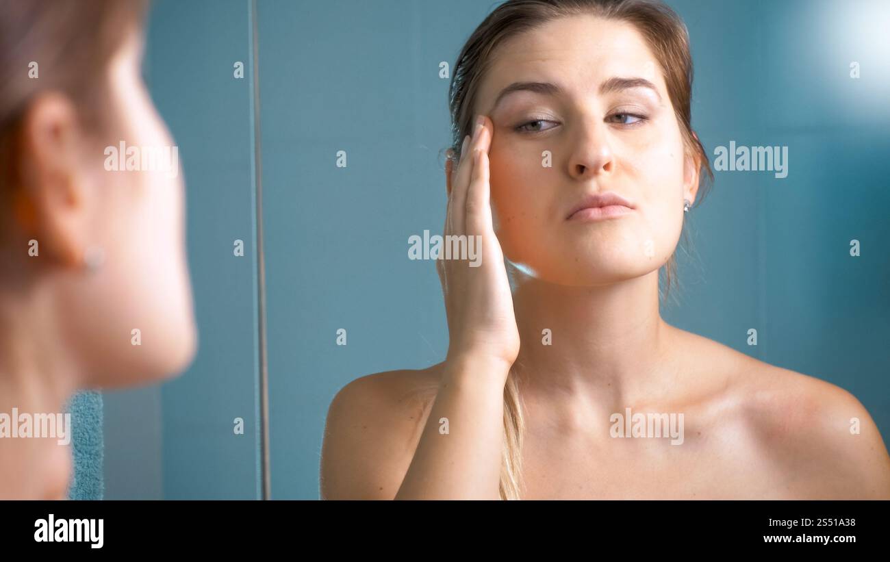 Beautiful brunette woman checking her face for aging wrinkles in ...