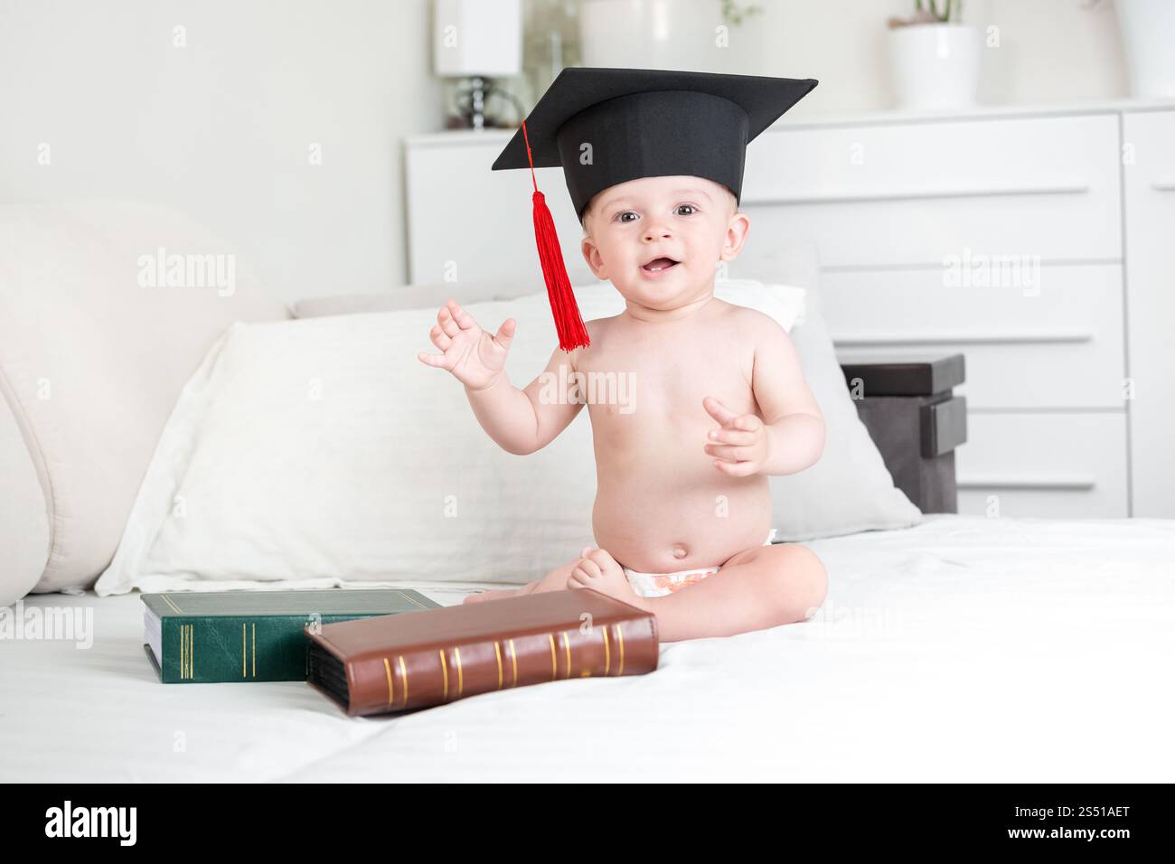 Smiling baby boy in black graduation hat looking in camera. Smiling ...