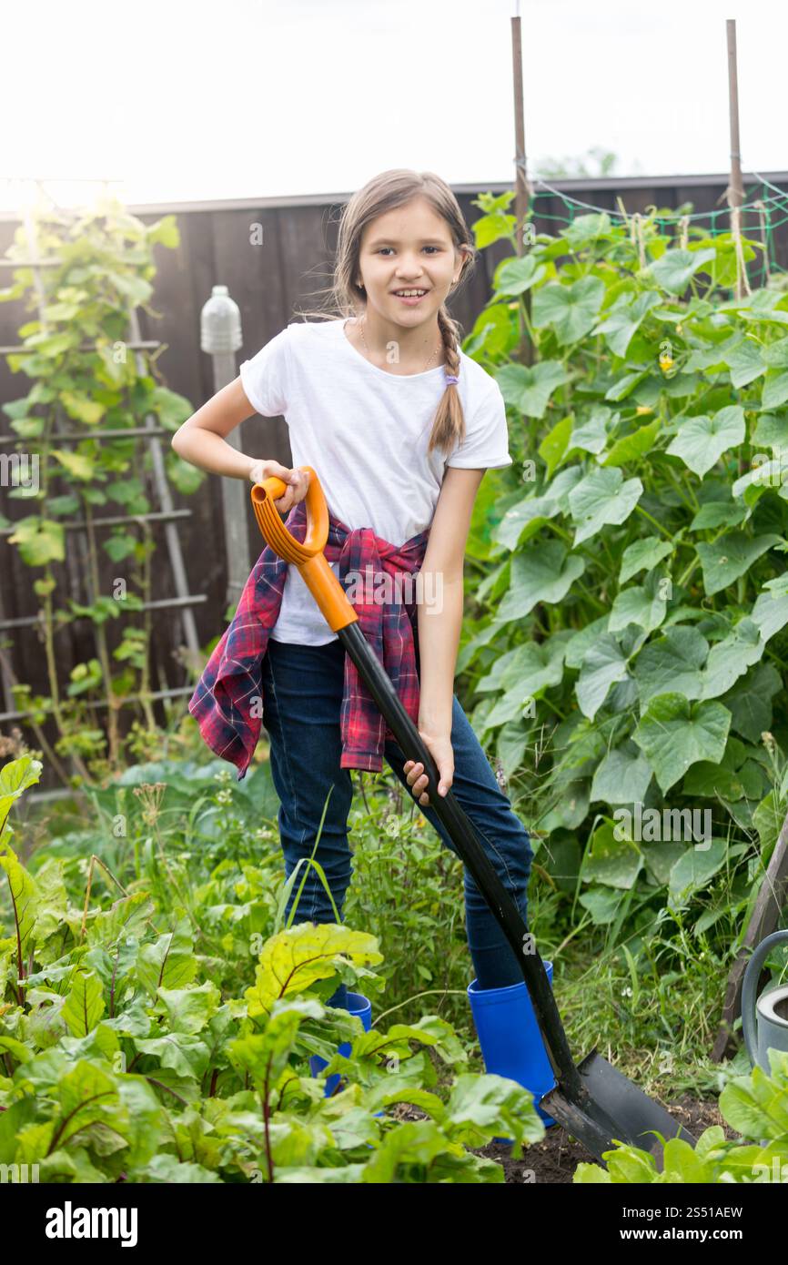 Beautiful young girl digging soil in garden with spade. Beautiful girl ...