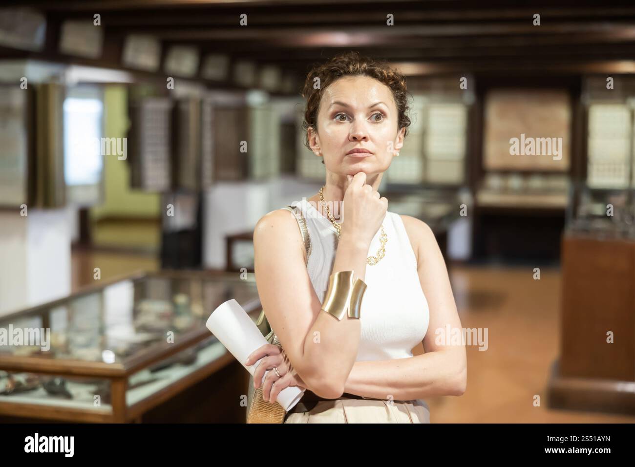 Positive woman admires the works of art on display while walking ...