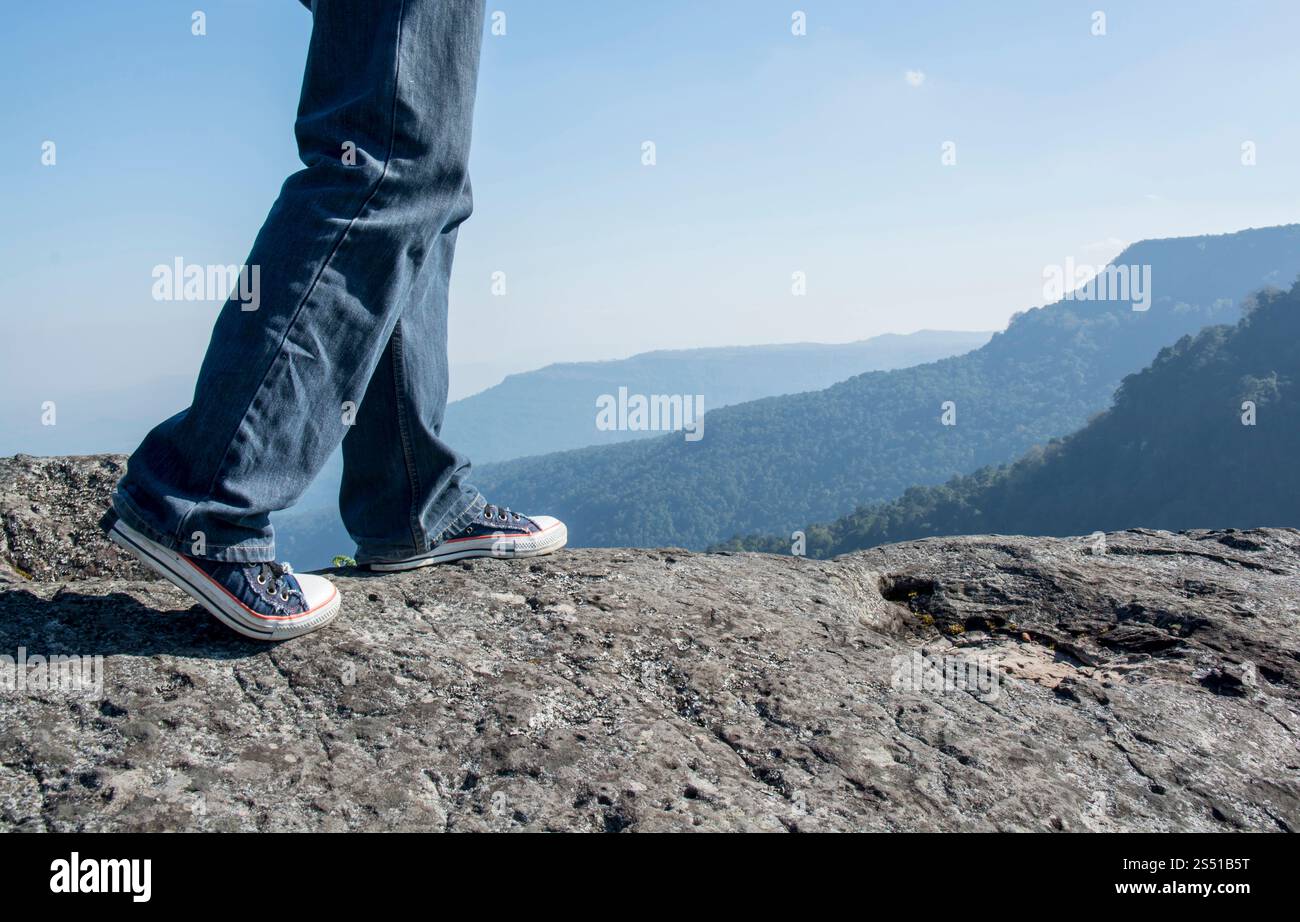 Man walking on edge of a cliff mountain top , travel concept Stock ...