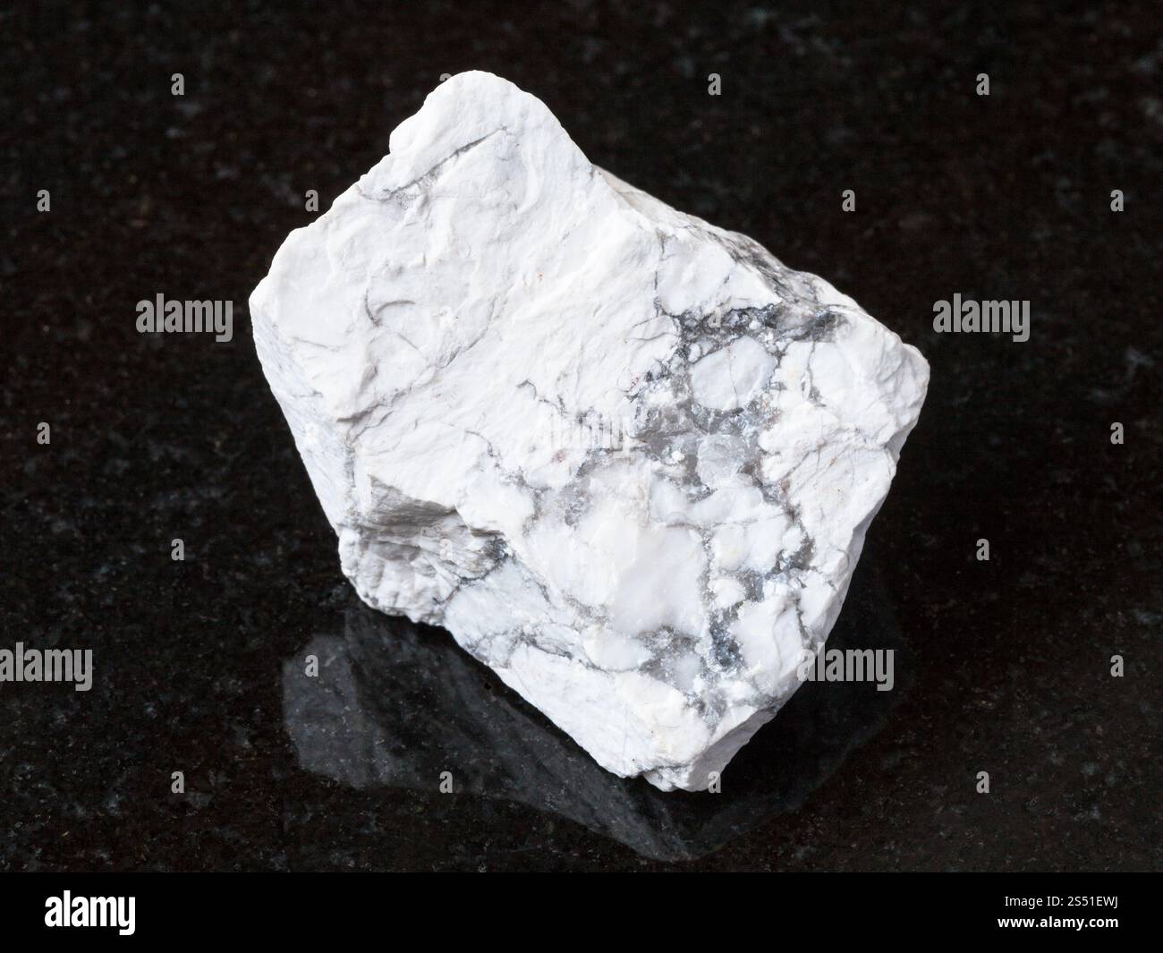 raw Howlite stone on black granite. macro shooting of natural rock ...