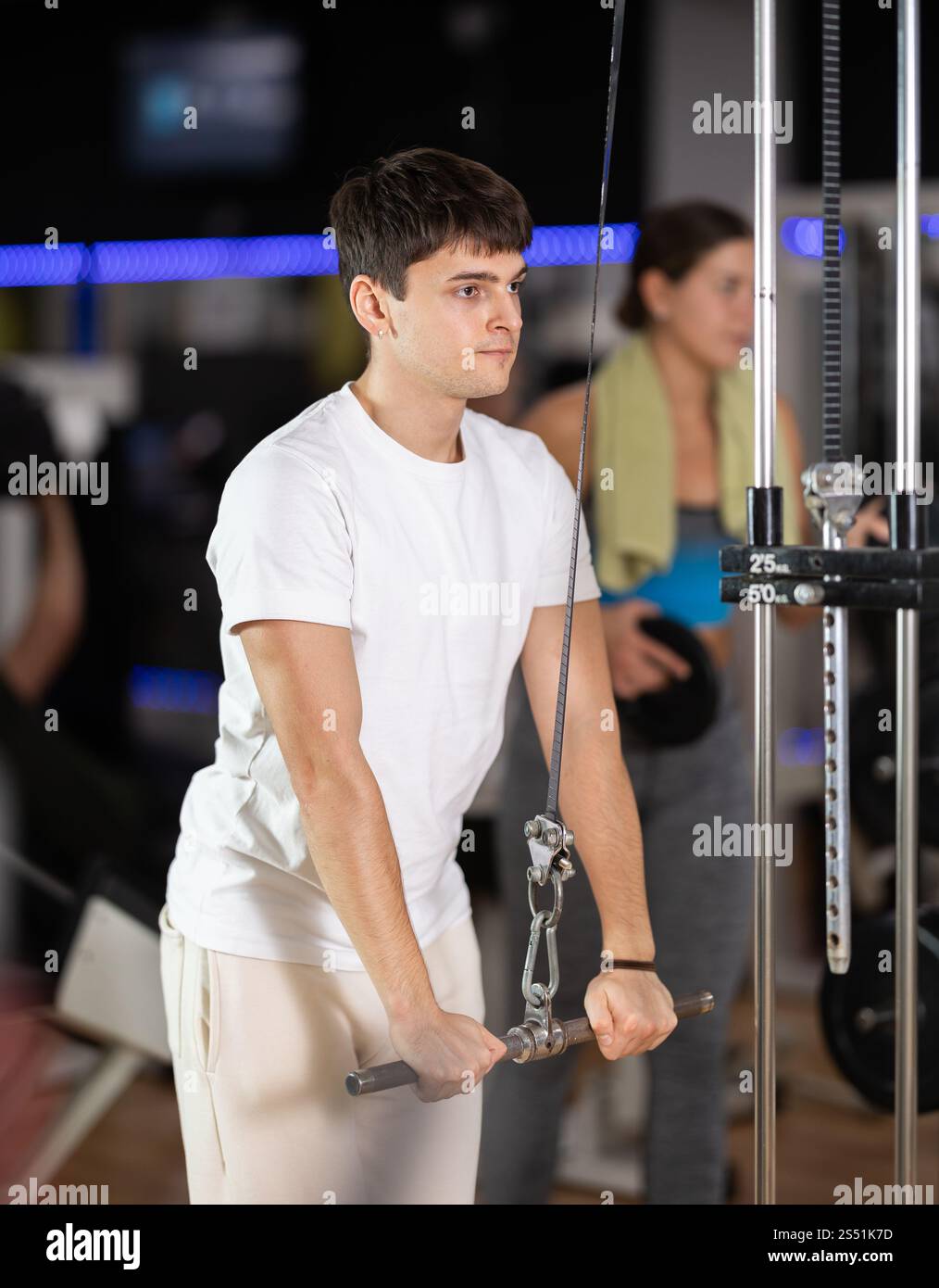 Guy in gym performs exercises for arm muscles using cable crossover ...