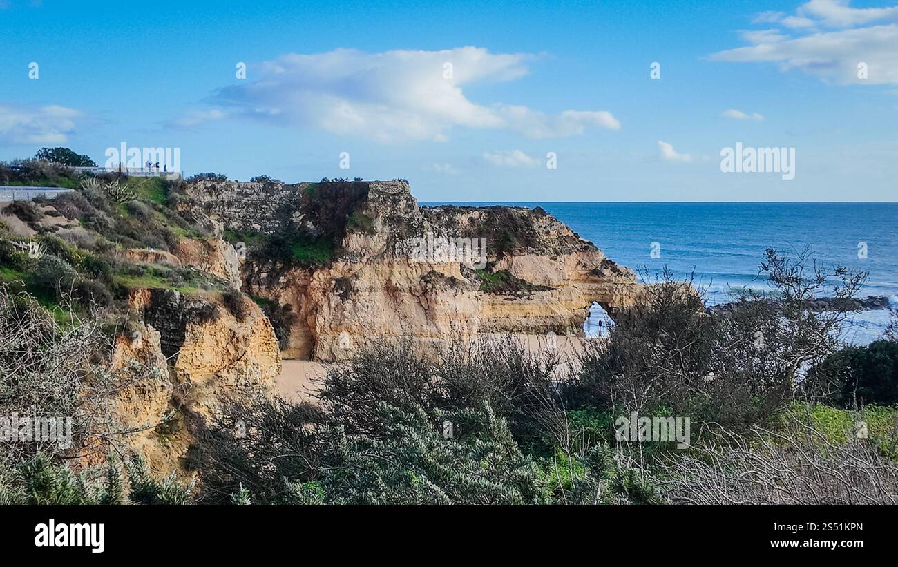 A cliff in the beach area of Portimão, Portugal, with blue skies and ...