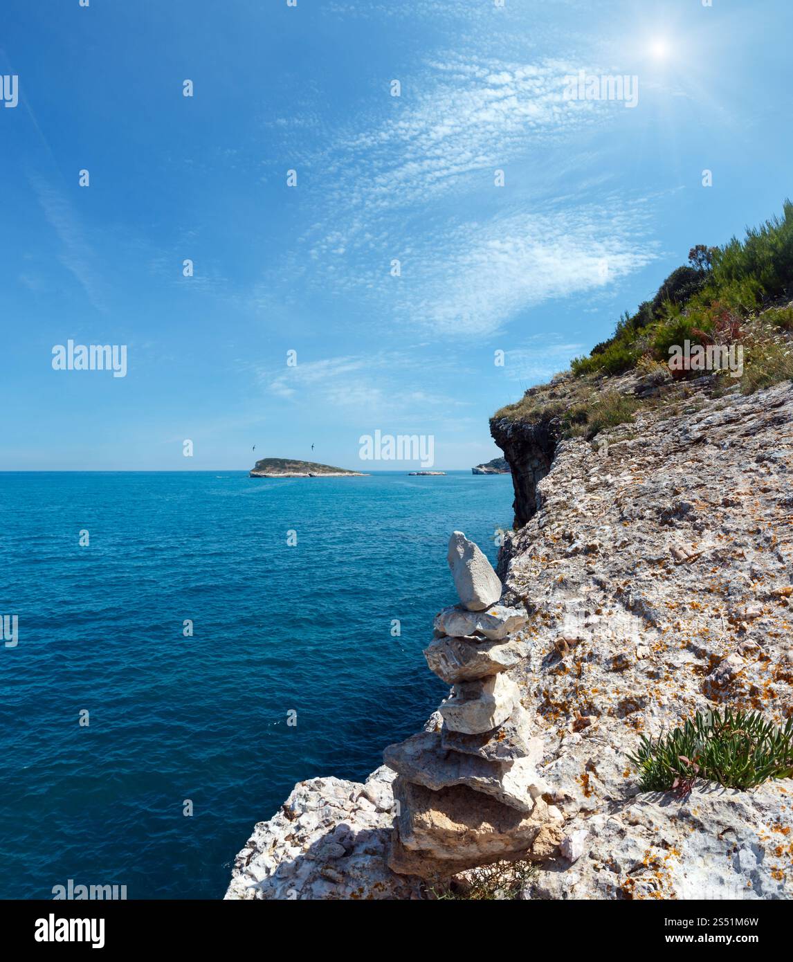 Stone pyramid on summer sunshiny rocky sea coast Baia Di Campi Vieste ...