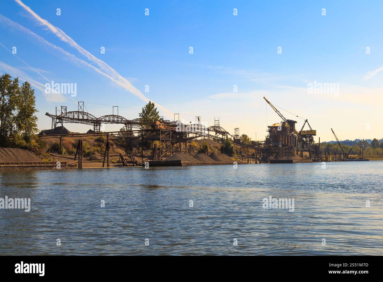 Industrial Facility on Riverfront with Construction Equipment under ...