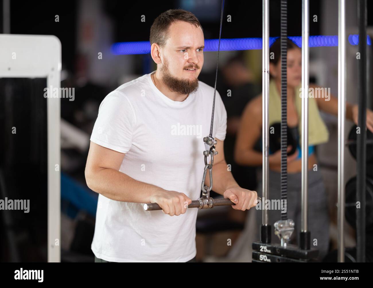 Man in gym performs exercises for arm muscles using cable crossover ...
