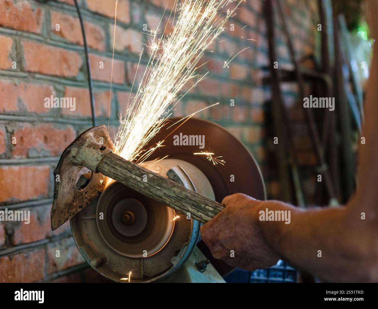 farmer sharpens garden tool on electric grindstone in rural shed Stock ...