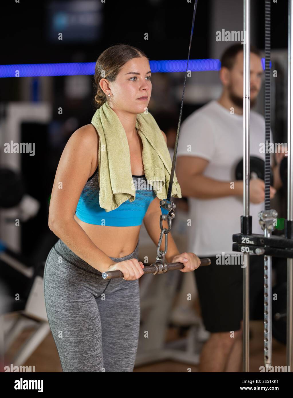Girl in gym performs exercises for arm muscles using cable crossover ...