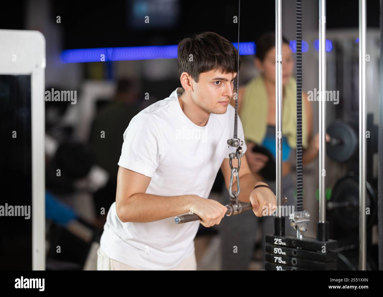 Guy in gym performs exercises for arm muscles using cable crossover ...