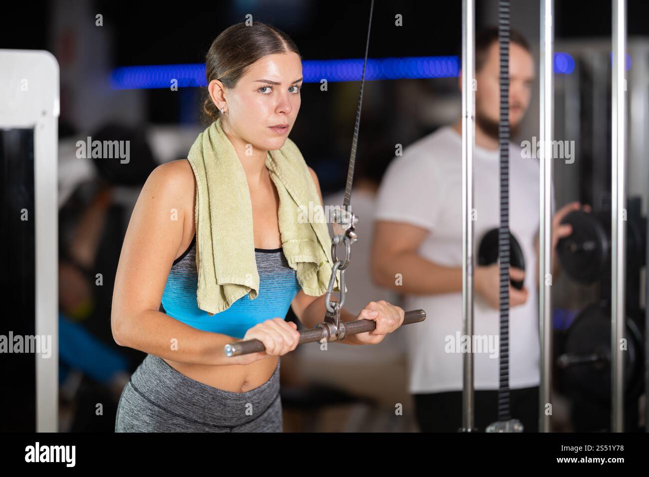 Girl in gym performs exercises for arm muscles using cable crossover ...