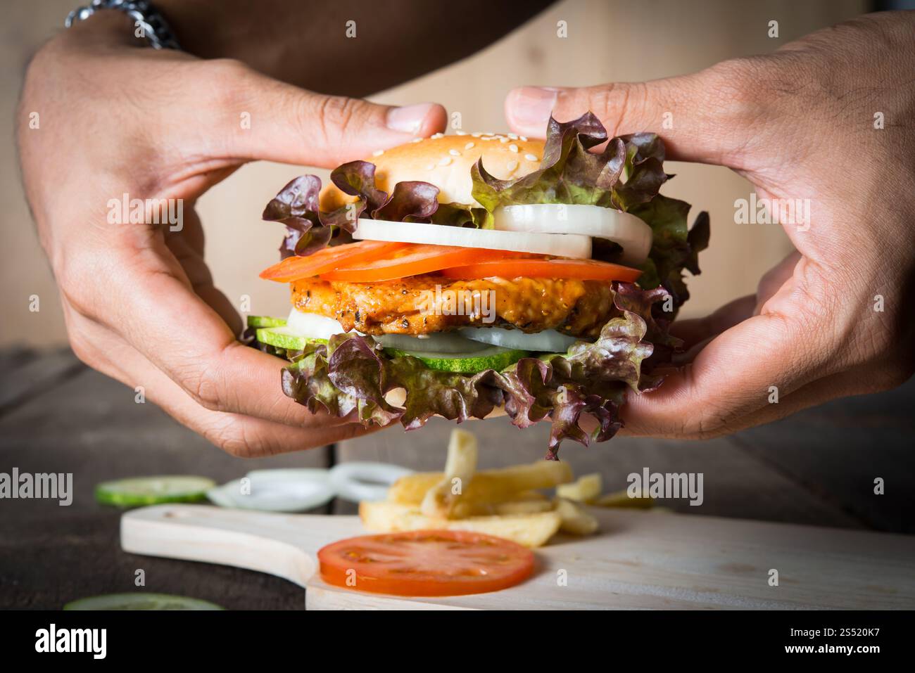 man holds burger with hands and potato chip Stock Photo - Alamy