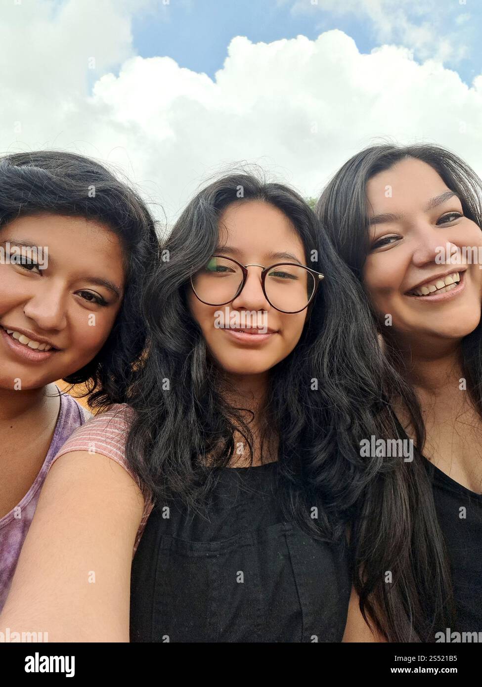 Three brunette Latin women use cell phones to make video calls and take ...