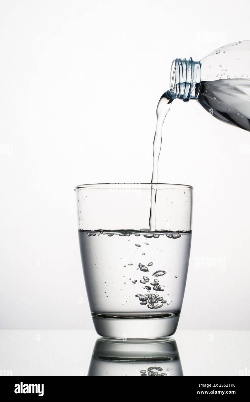Close up of pouring water splashing from glass isolated on white. Close ...
