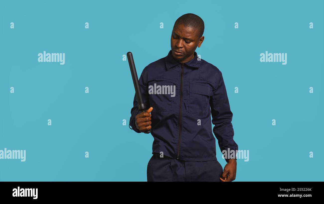 Security guard removing baton from belt, preparing to attack suspects ...