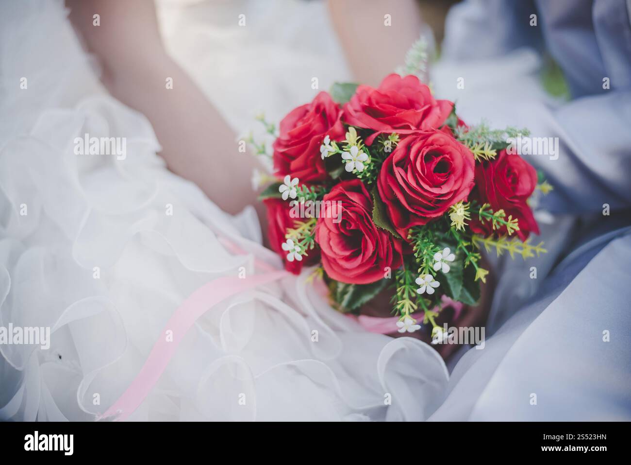 Bride holds a wedding red rose bouquet in hands, the groom hugs . Bride ...