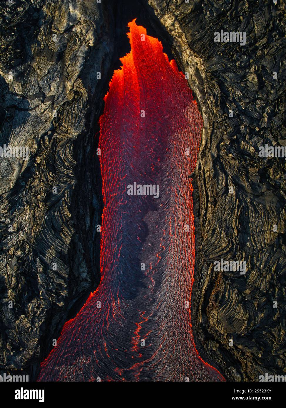 Aerial view of vibrant molten lava flowing through a volcanic fissure ...