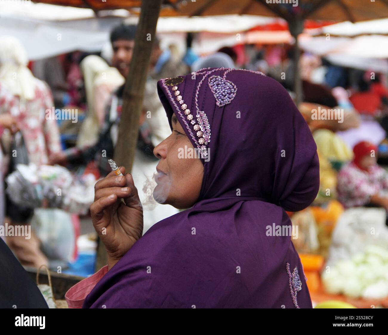 An Indonesian Moslem woman wearing a purple headscarf or hijab and ...