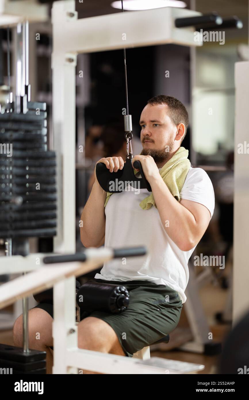 Man in gym performs exercises for arm muscles using cable crossover ...