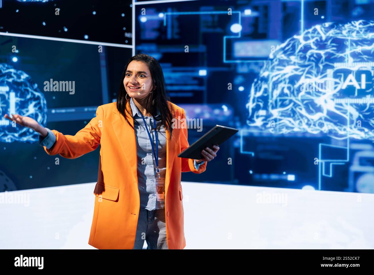 Woman using microphone and tablet to do presentation at workshop exploring developments in AI ...