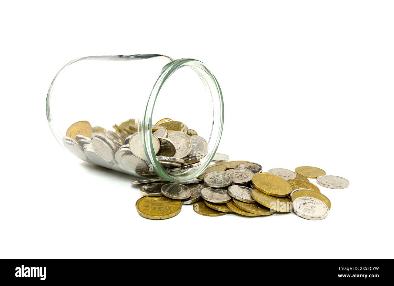 Coins spill from a glass jar on a white background creating a messy ...