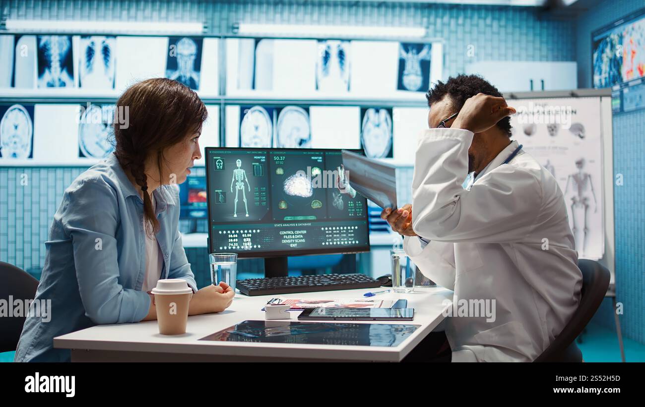 African american physician presenting the x ray diagnostics results to a patient, examining the ...