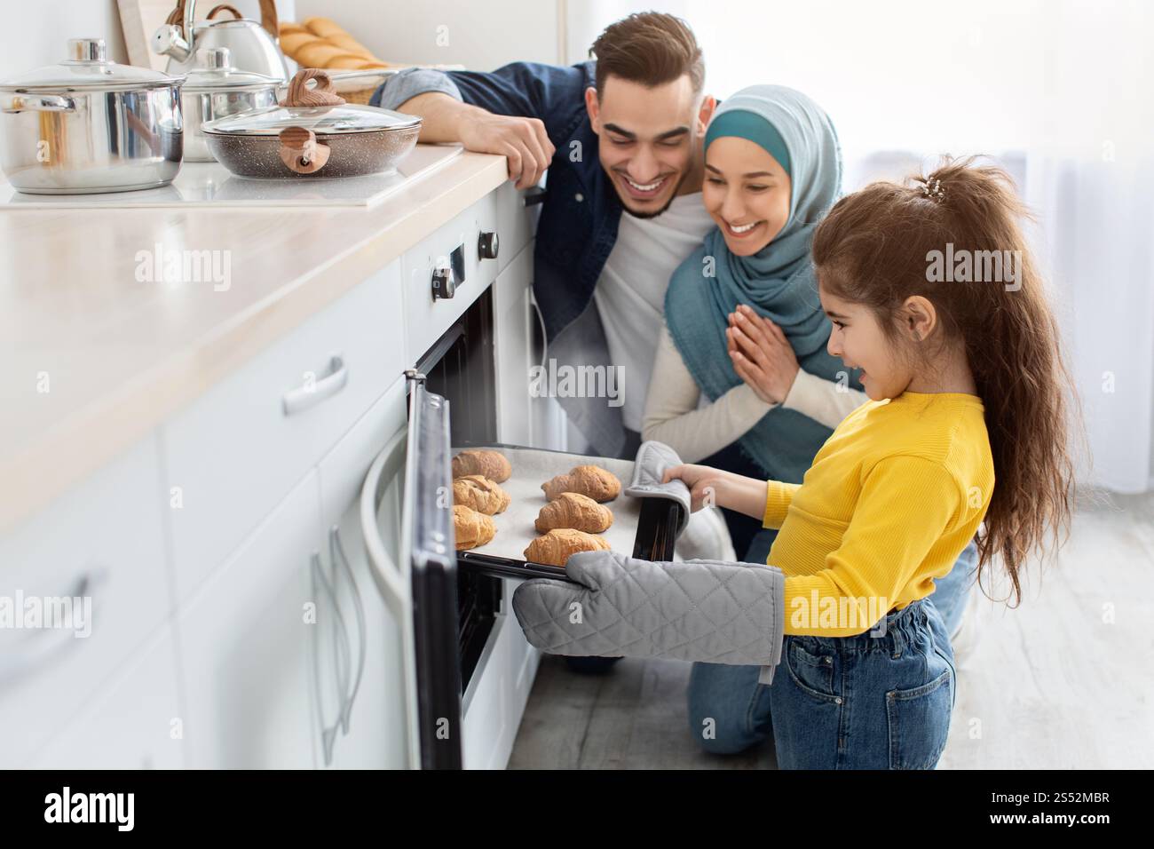 Happy muslim family of three baking croissants together in kitchen ...
