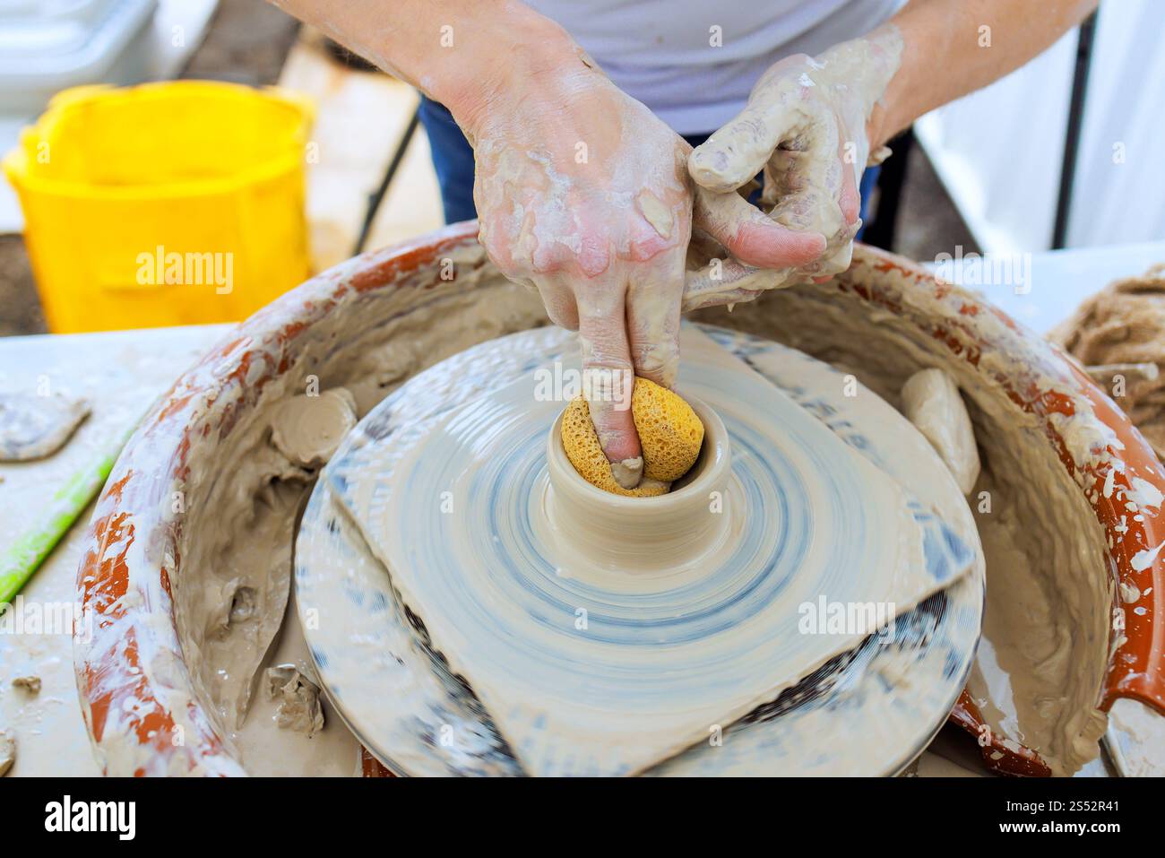 Potter hands mold clay on pottery wheel in an outdoor workshop ...