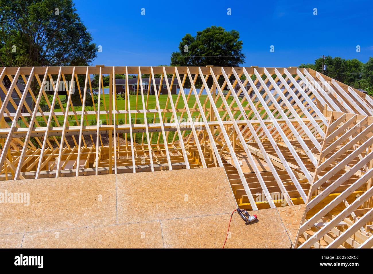 Wooden beams form roof structure over house, showcasing carpentry work ...