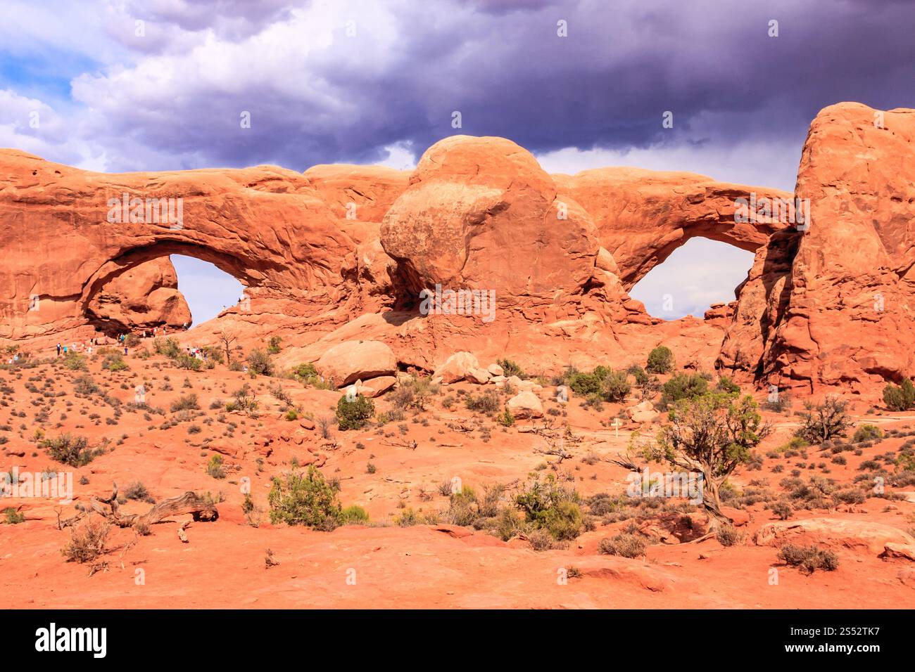 A desert landscape with a large rock formation with two arches. The ...