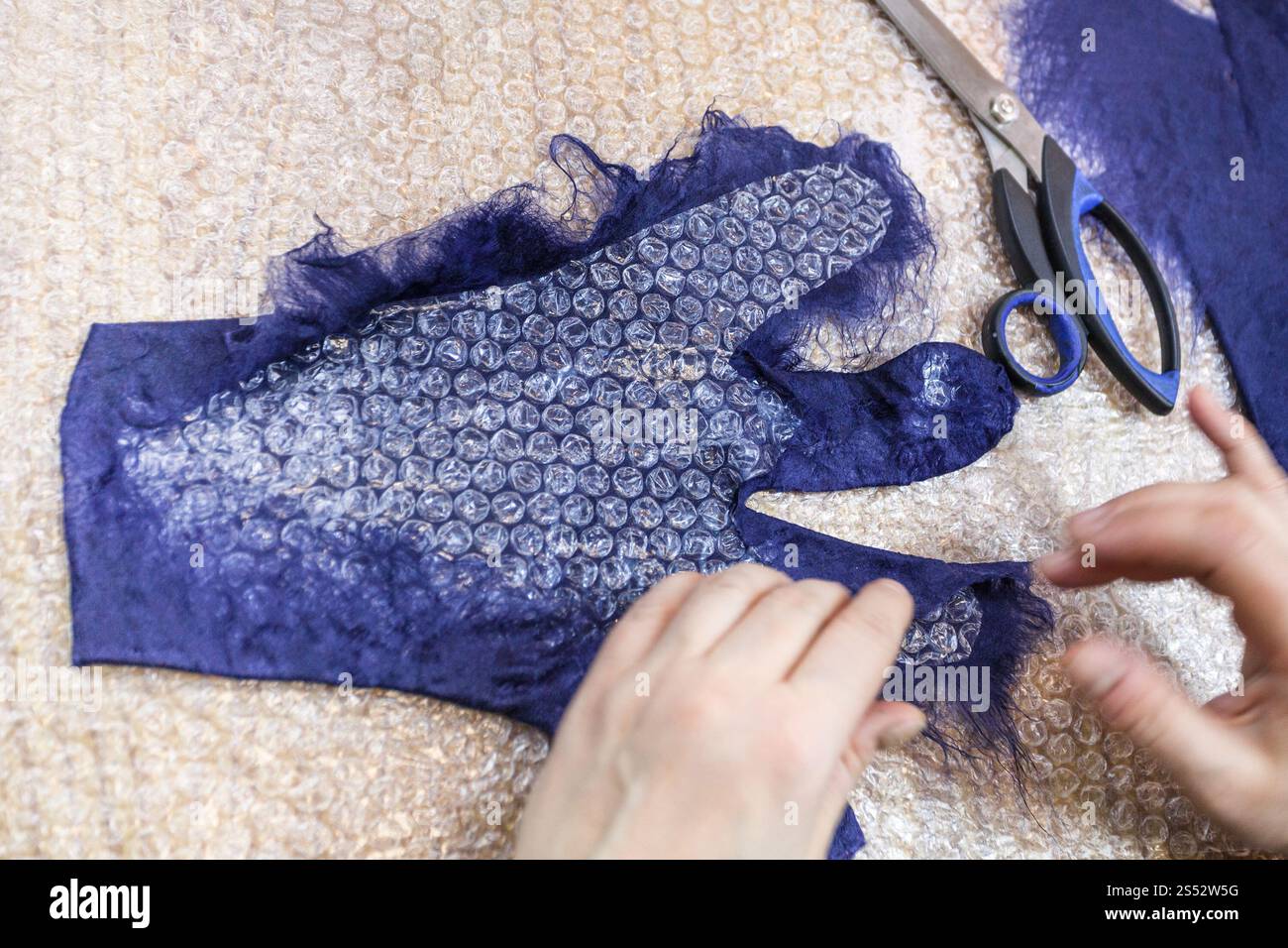 workshop of hand making a fleece gloves from blue Merino sheep wool ...