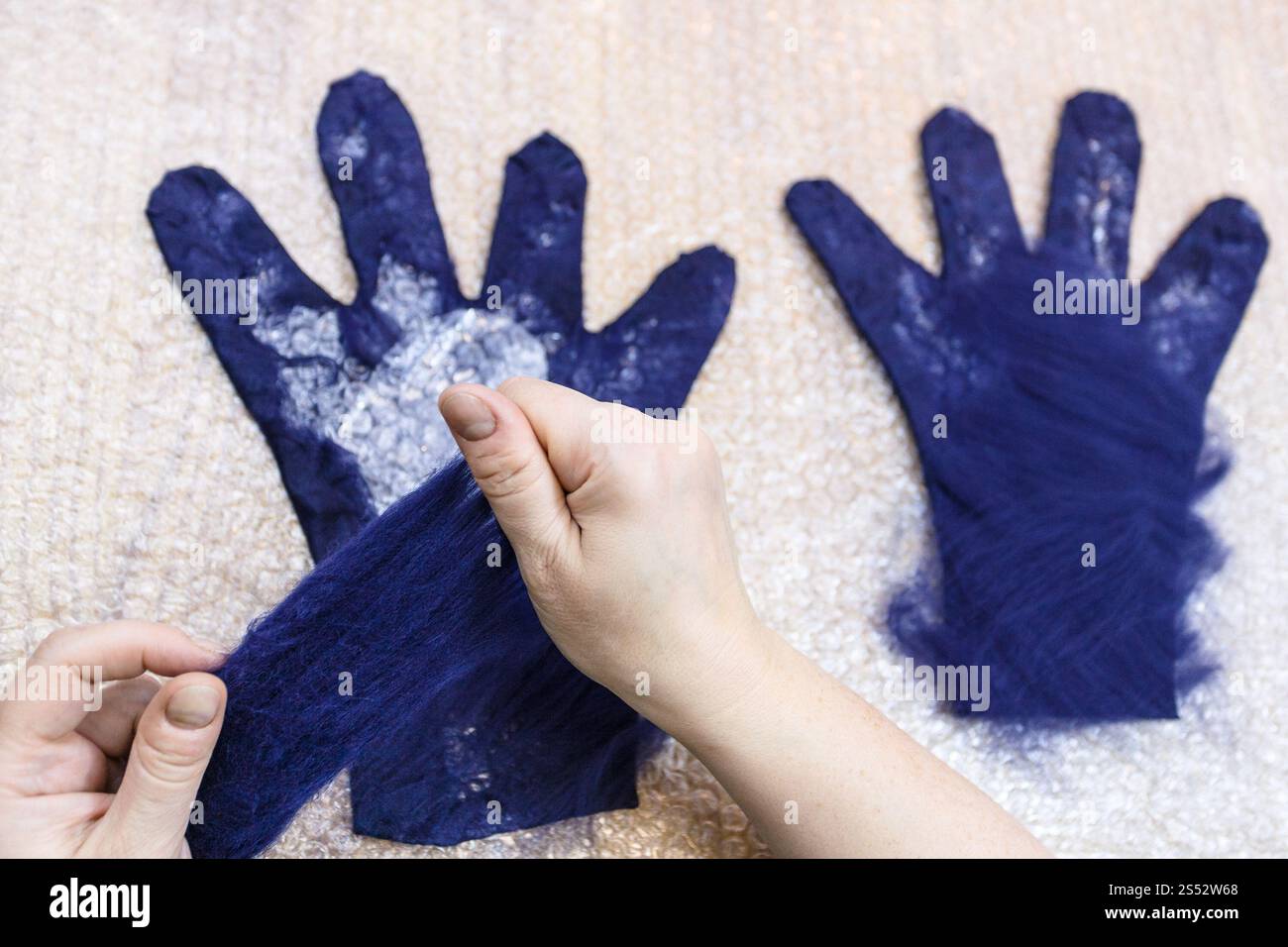workshop of hand making a fleece gloves from blue Merino sheep wool ...