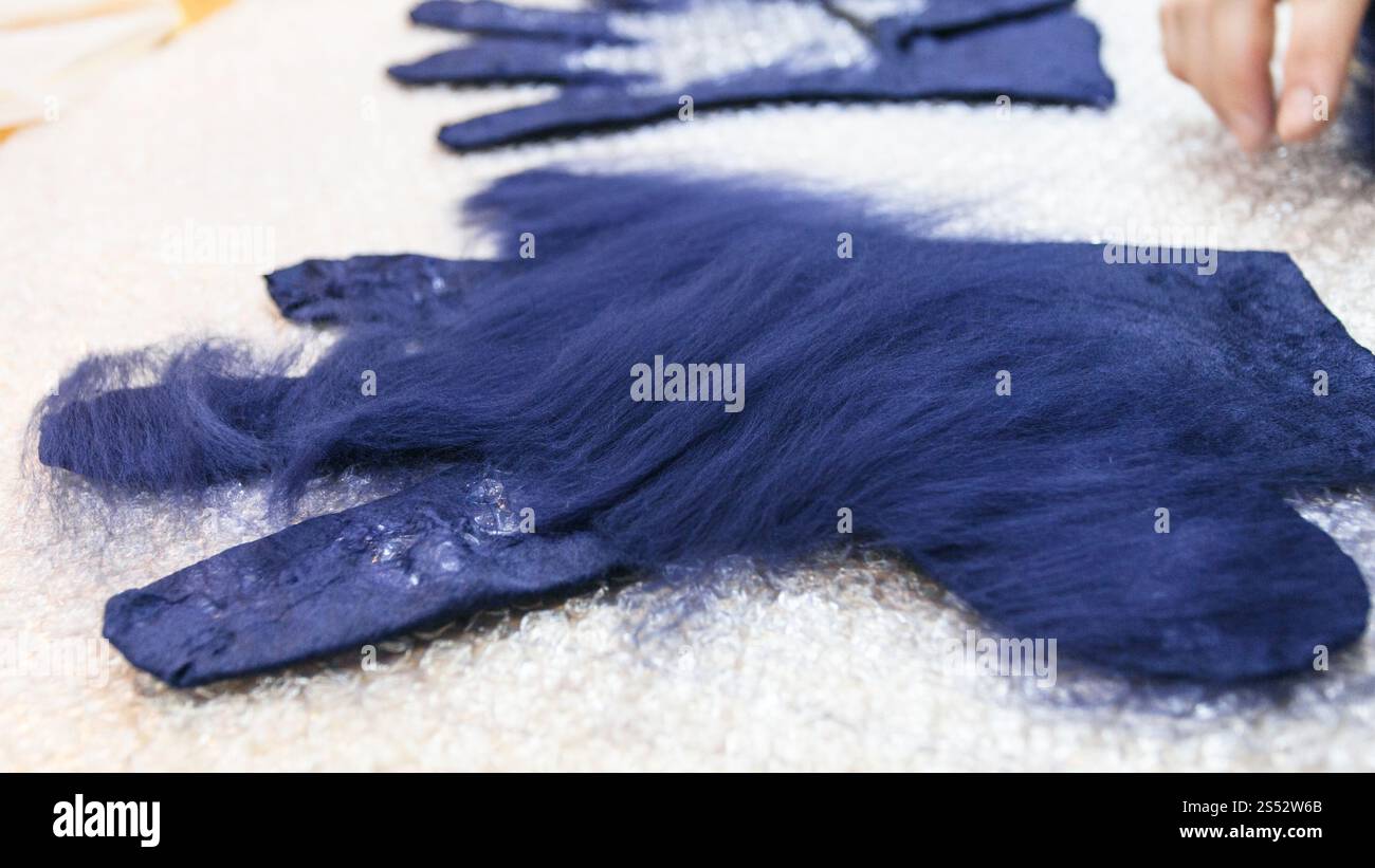 workshop of hand making a fleece gloves from blue Merino sheep wool ...