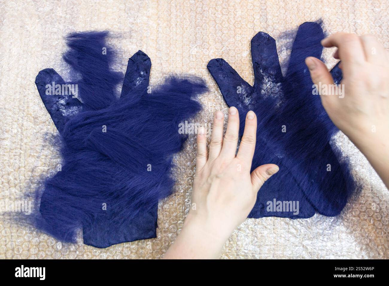 workshop of hand making a fleece gloves from blue Merino sheep wool ...